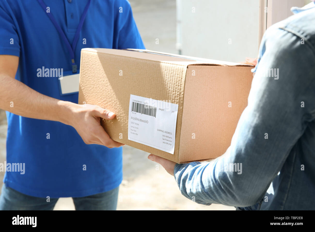 Woman receiving parcel from delivery man Stock Photo - Alamy