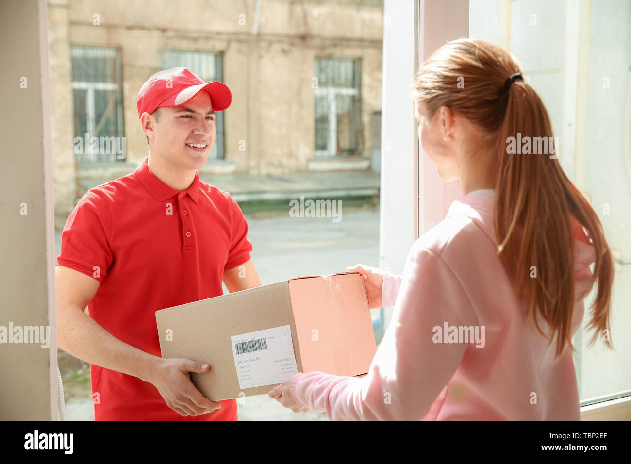 Woman receiving parcel from delivery man Stock Photo - Alamy