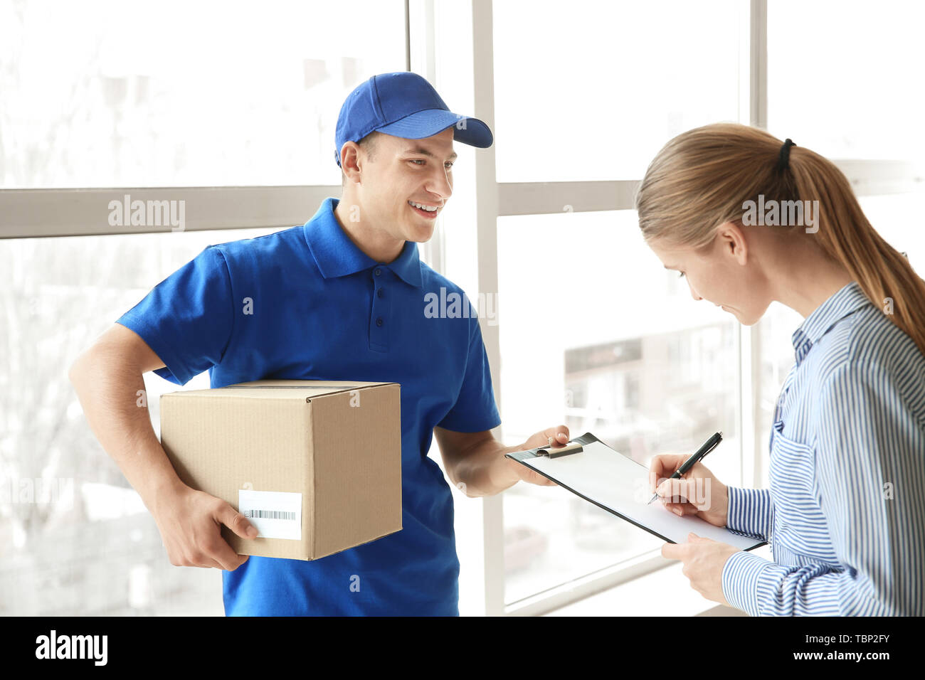 Woman signing documents to confirm receiving of order from delivery ...