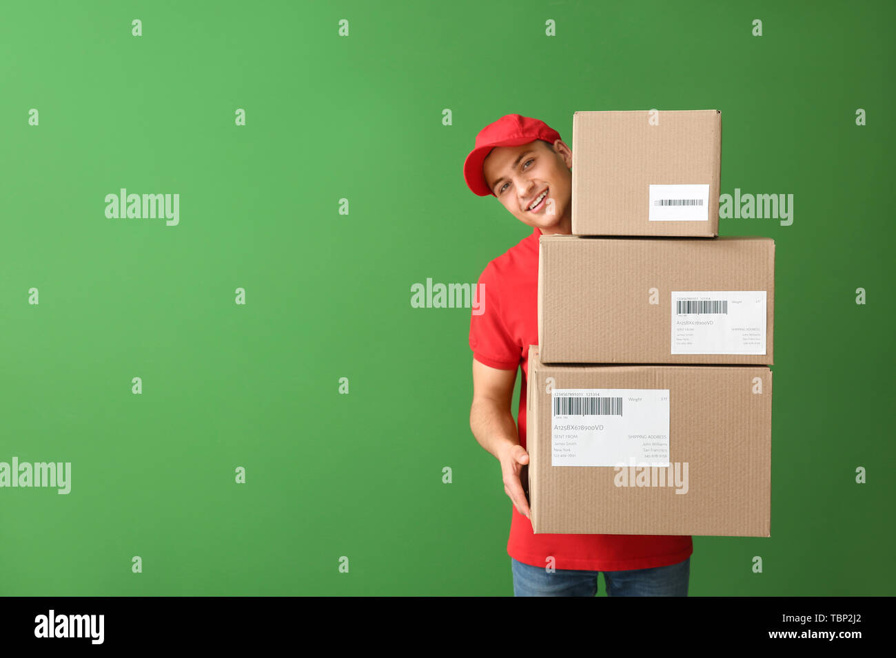 Delivery man with boxes on color background Stock Photo - Alamy