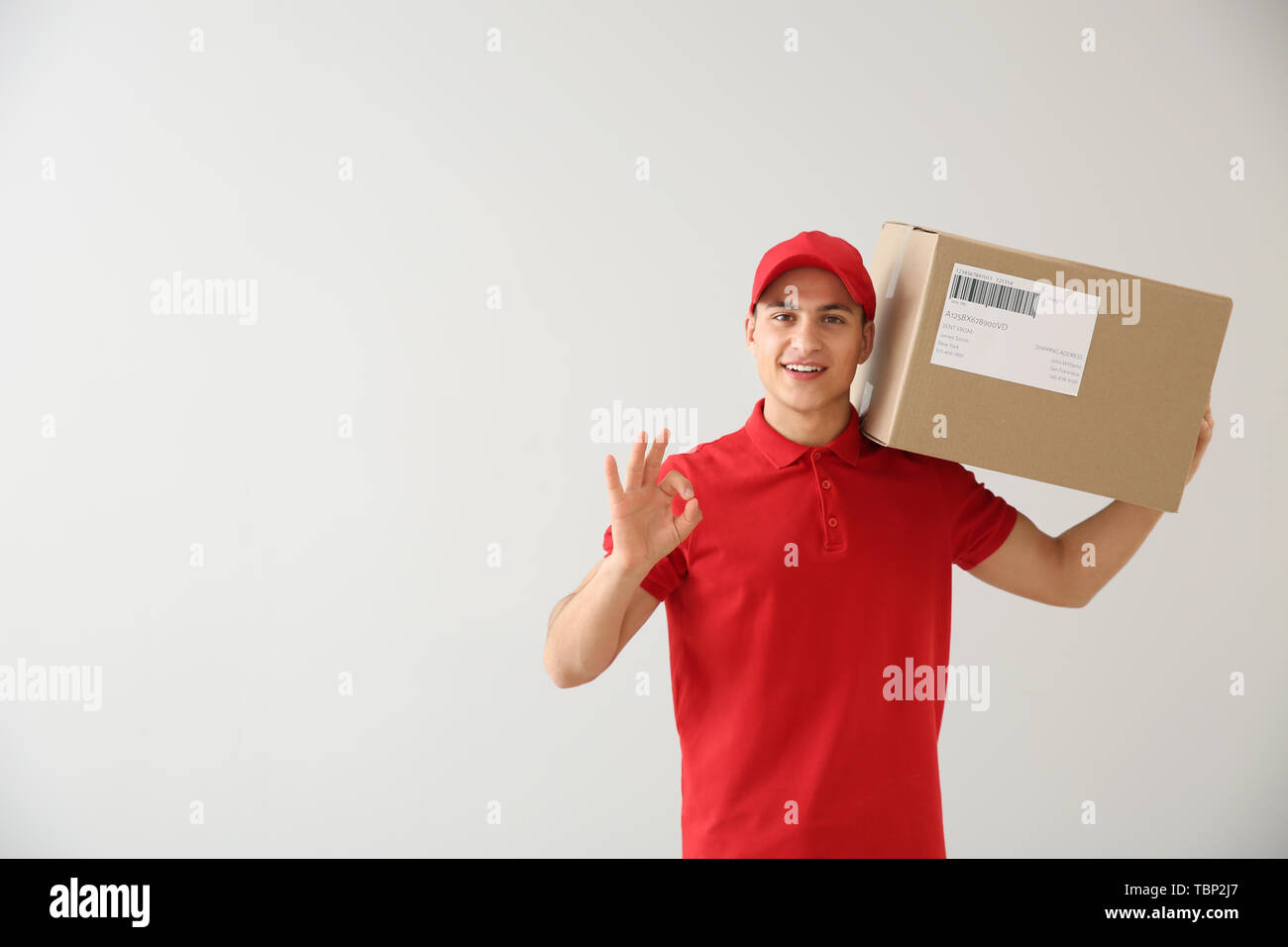 Delivery man with box showing OK on white background Stock Photo - Alamy