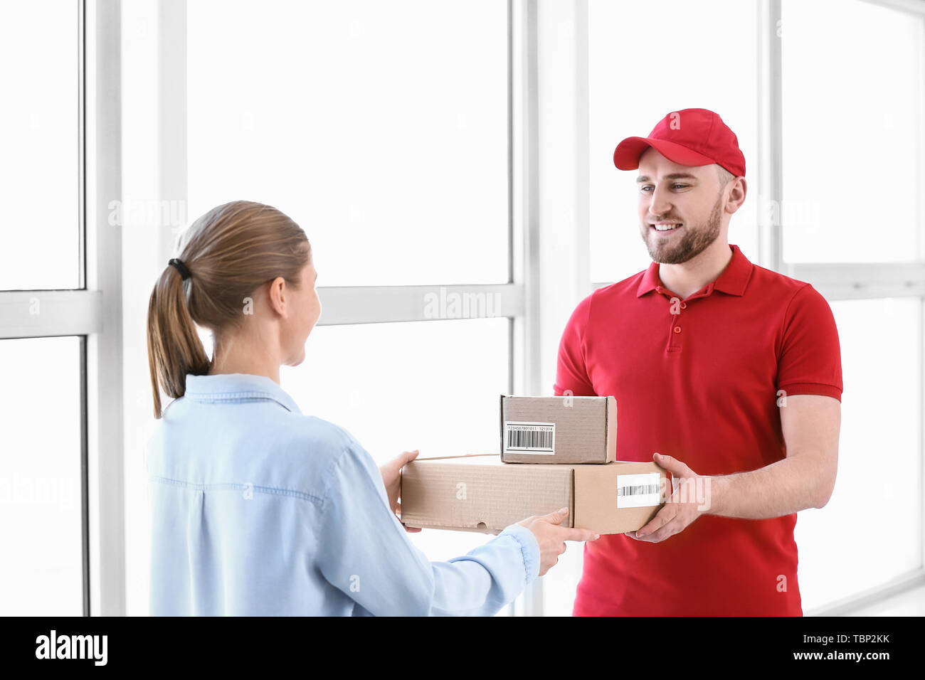 Woman receiving parcels from delivery man Stock Photo - Alamy