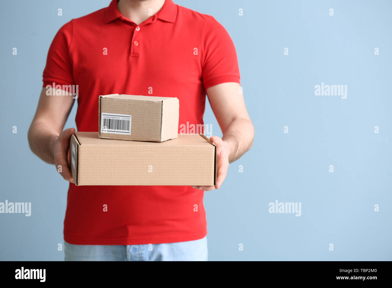 Delivery man with boxes on color background Stock Photo - Alamy