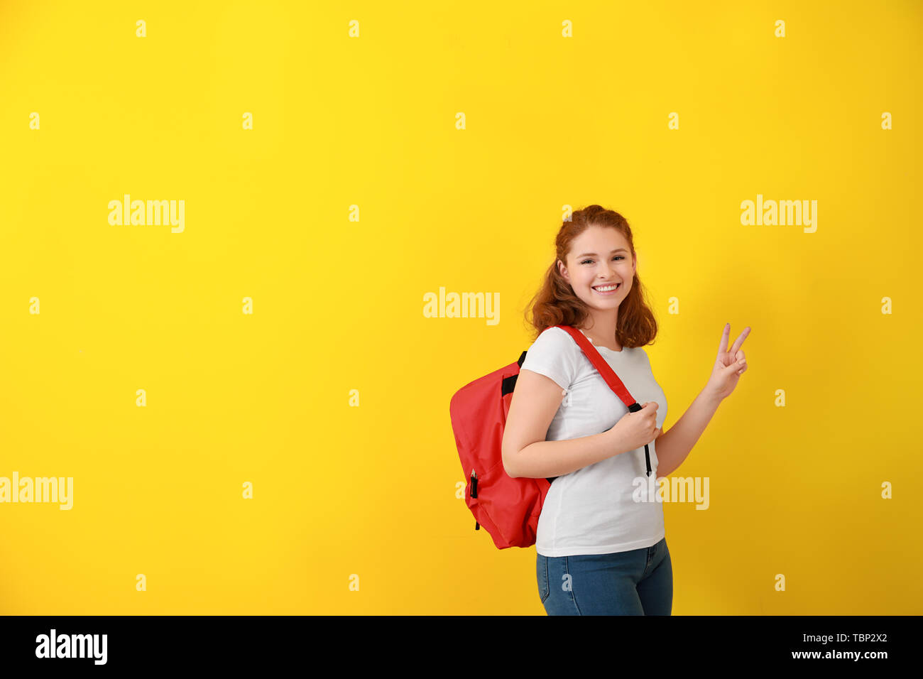 Cute teenage girl showing victory gesture on color background Stock ...