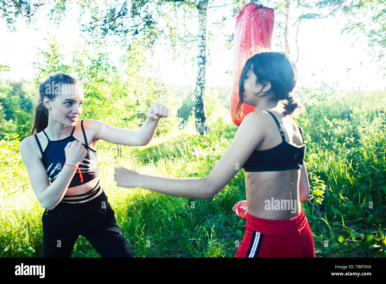two diverse nations girls fighting boxing outside in green park, sport ...