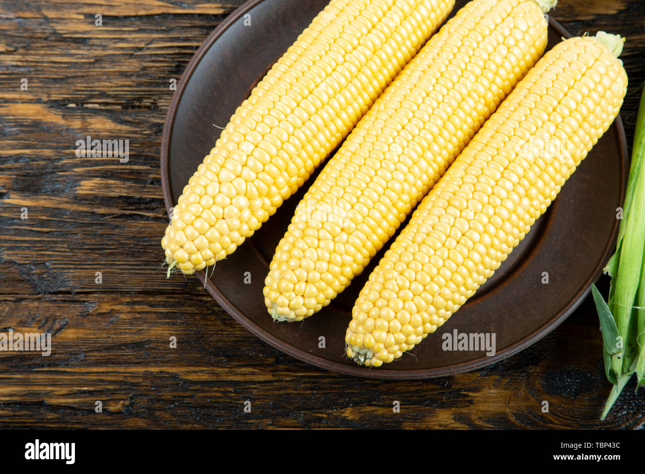 corn cobs harvest on a brown wooden background. clearly visible texture ...