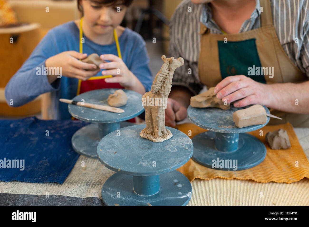 Little clay giraffe. Cute handsome pupil and his art teacher sculpting ...