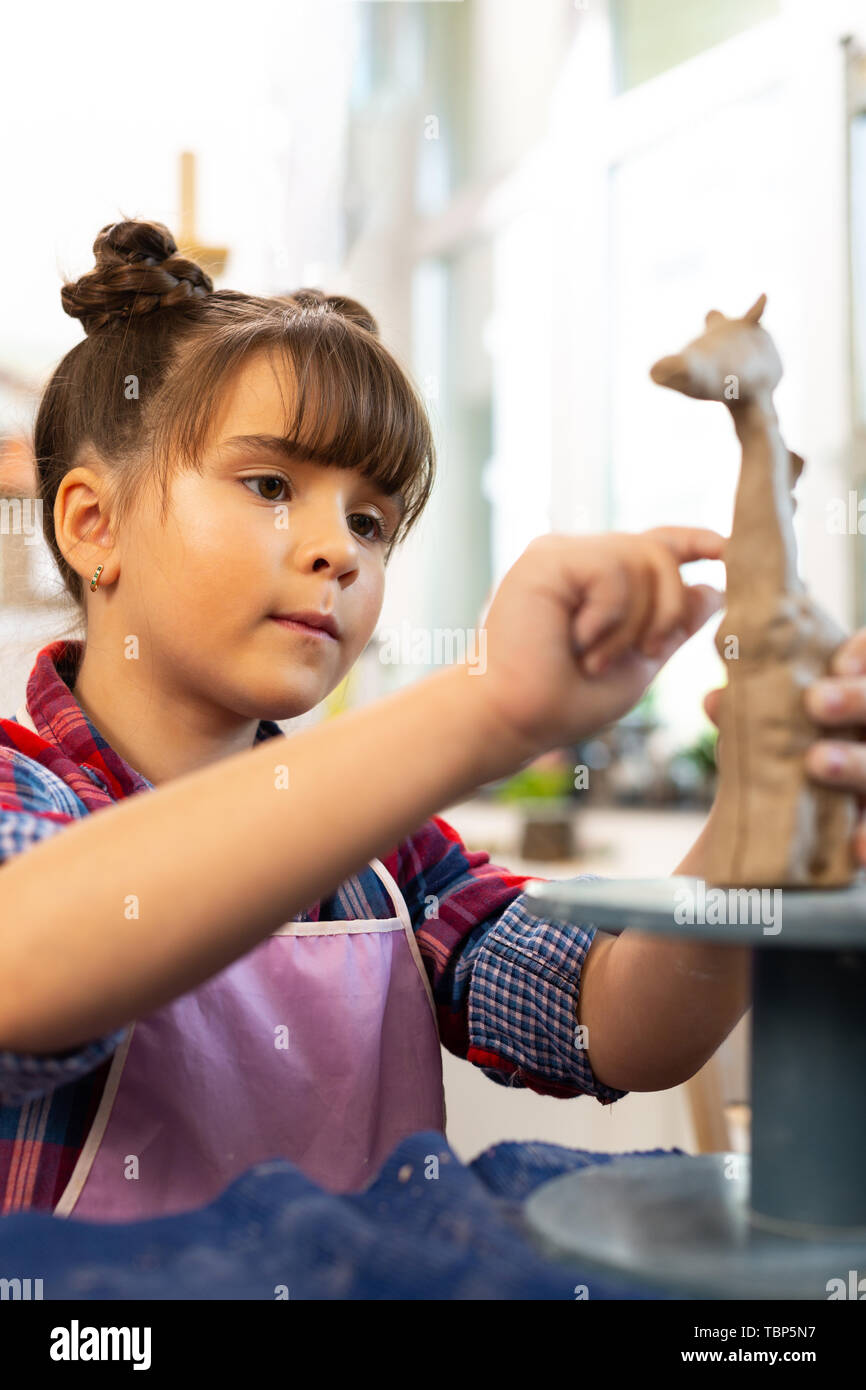 Modeling clay giraffe. Talented dark-eyed beautiful girl modeling clay ...