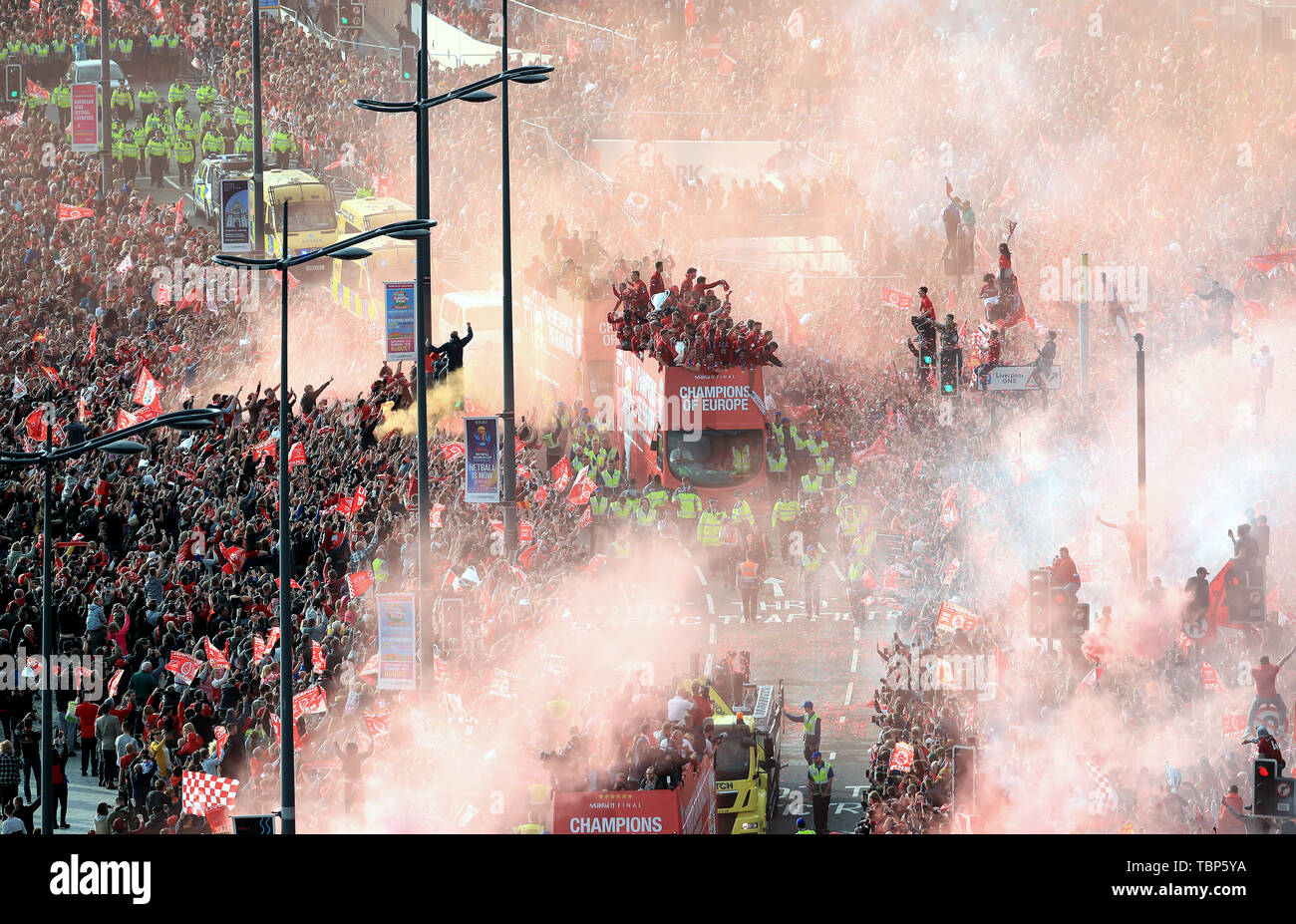 Flares are set off as the Liverpool bus passes through the crowds ...