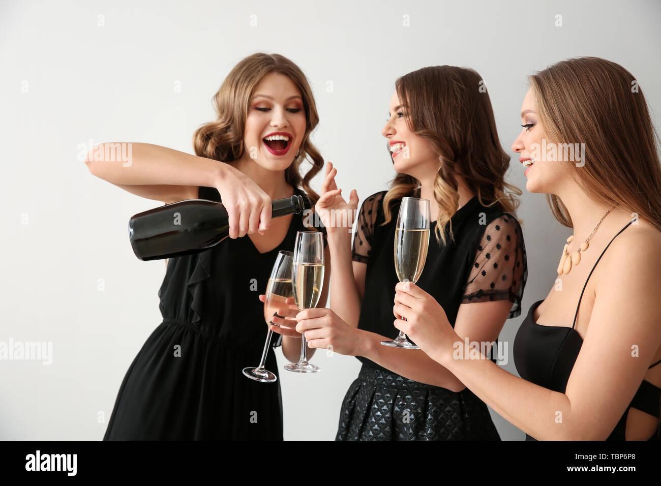 Beautiful young women drinking champagne on light background Stock ...