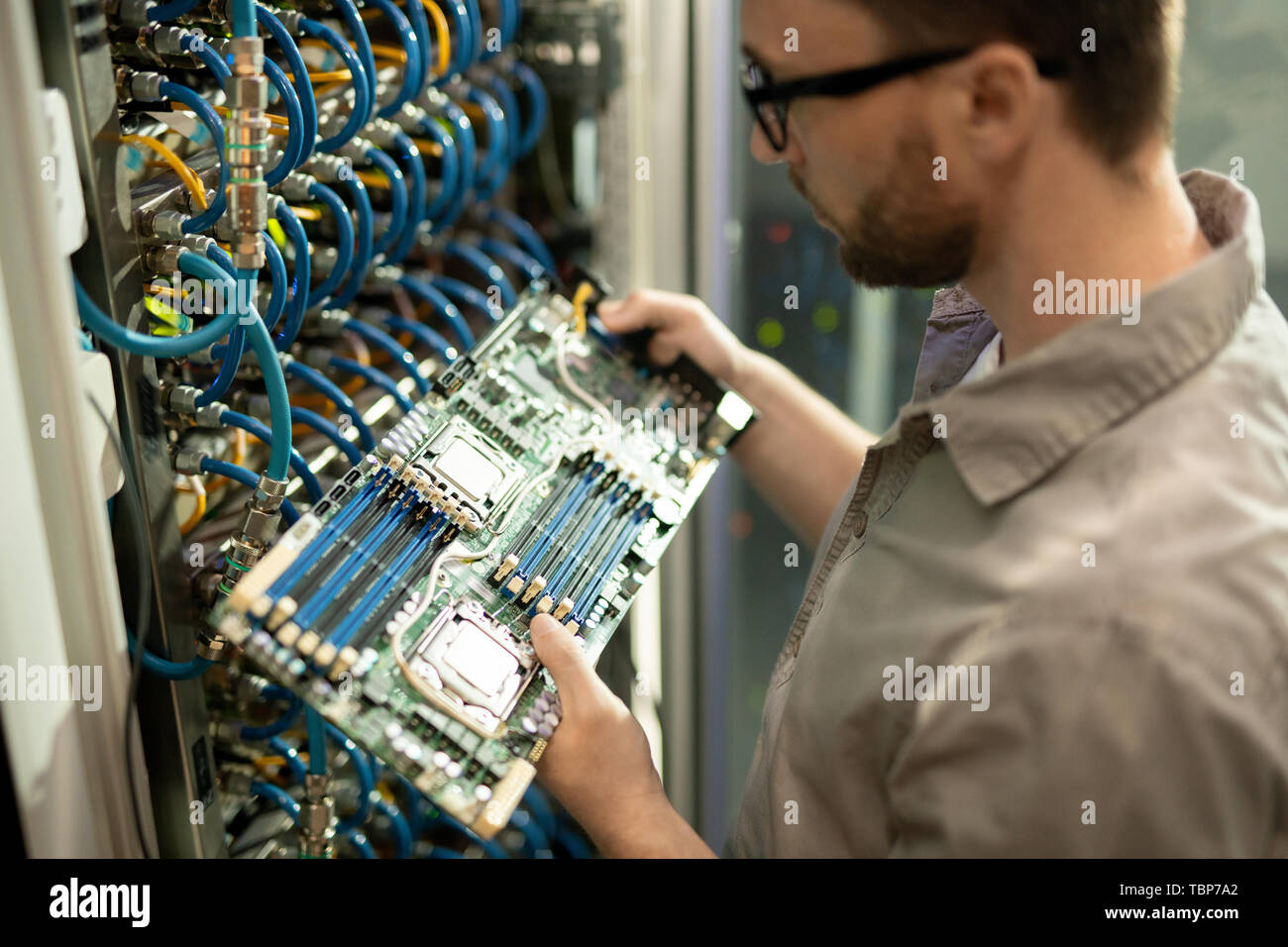 Close-up of serious bearded IT support specialist standing by cabinet ...