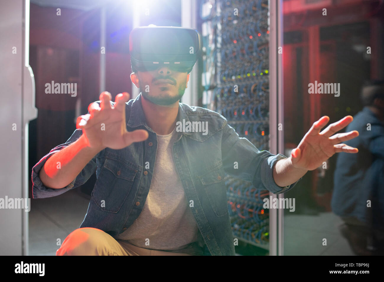 Serious concentrated young Arabian IT engineer with beard crouching on ...