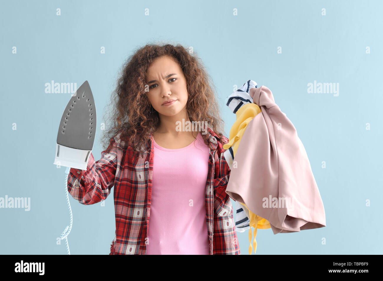 Stressed woman with iron and clothes on grey background Stock Photo - Alamy