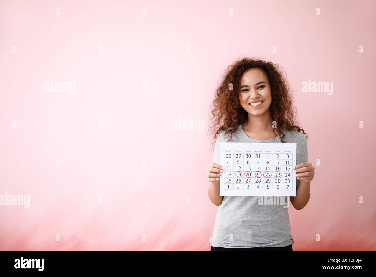 African-American woman holding calendar with marked days of ...