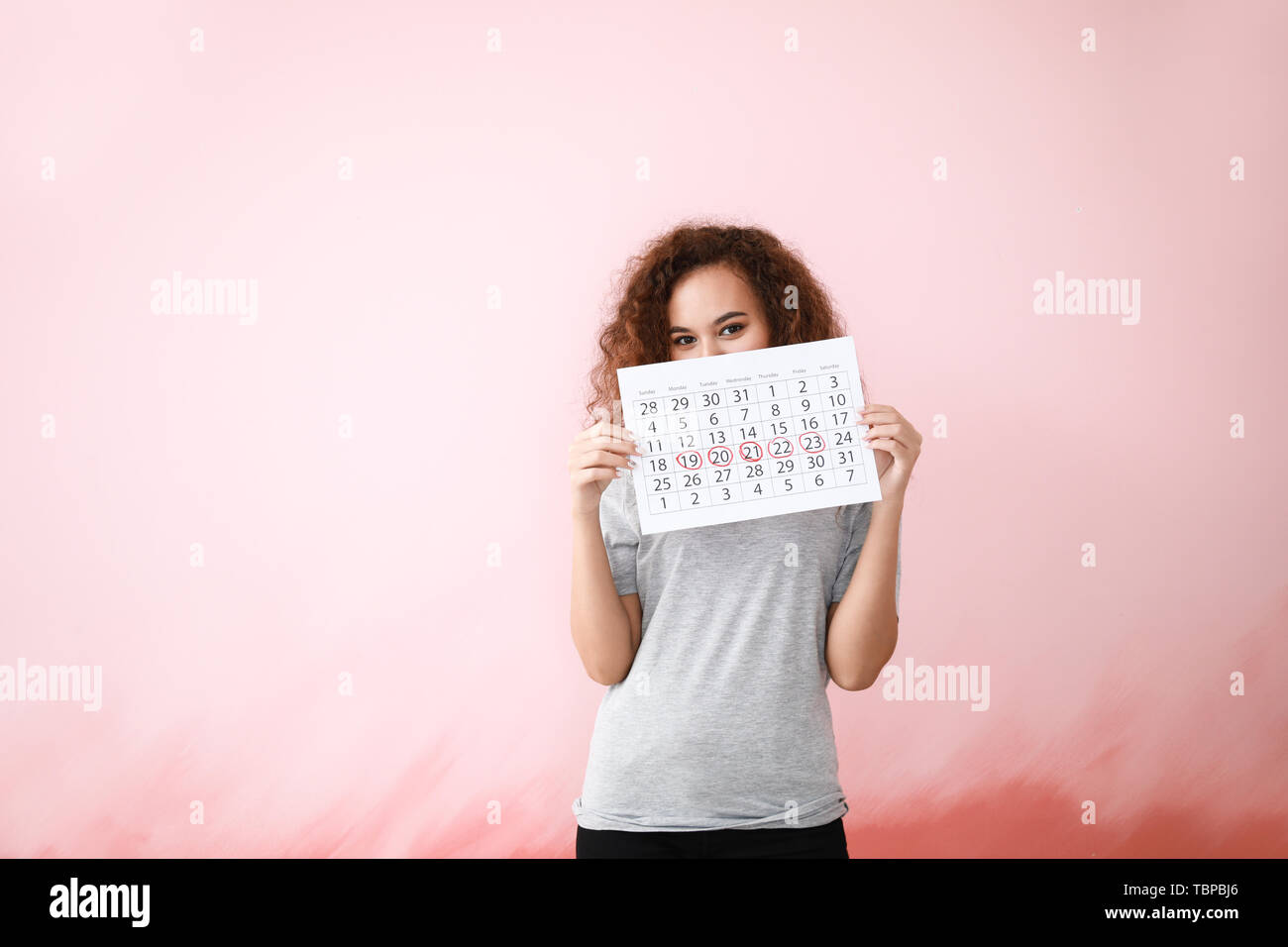 African-American woman holding calendar with marked days of ...