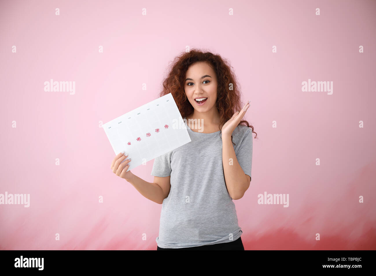 African-American woman holding calendar with marked days of ...