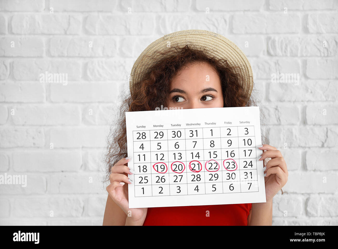 African-American woman holding calendar with marked days of ...