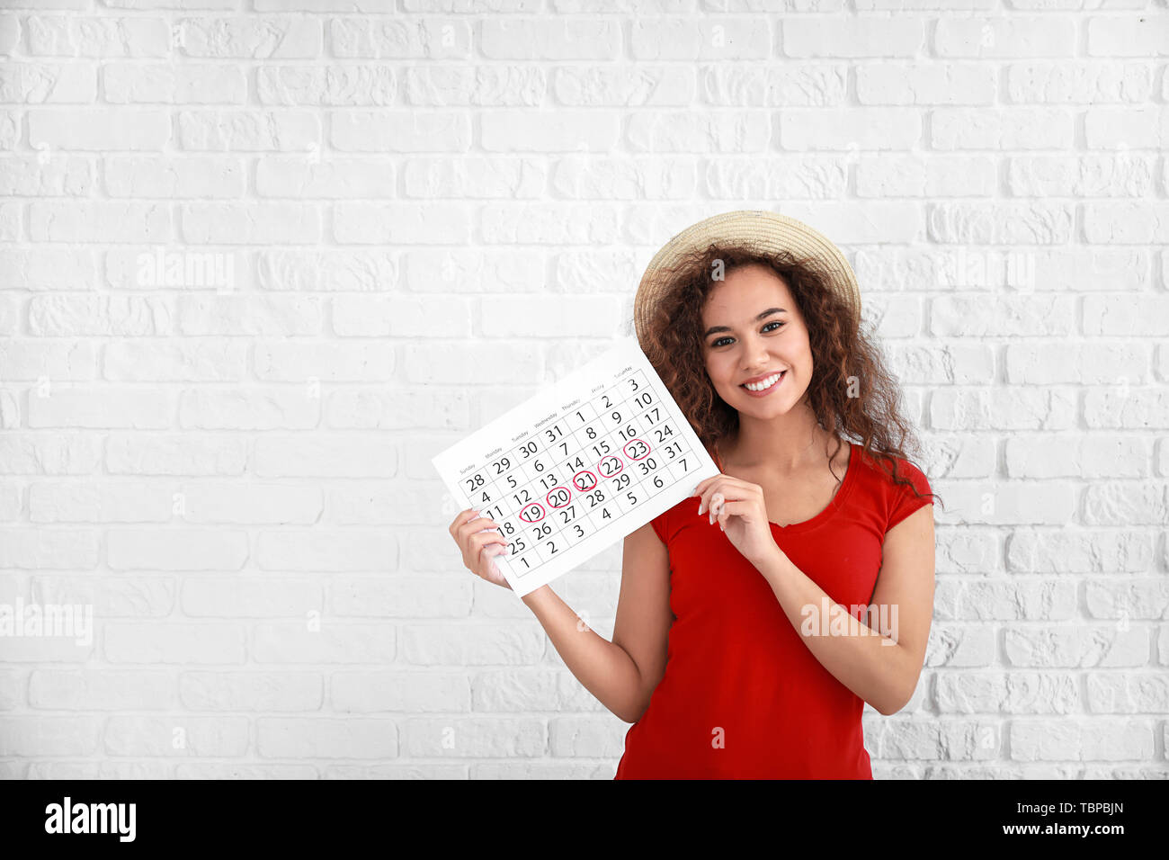 African-American woman holding calendar with marked days of ...