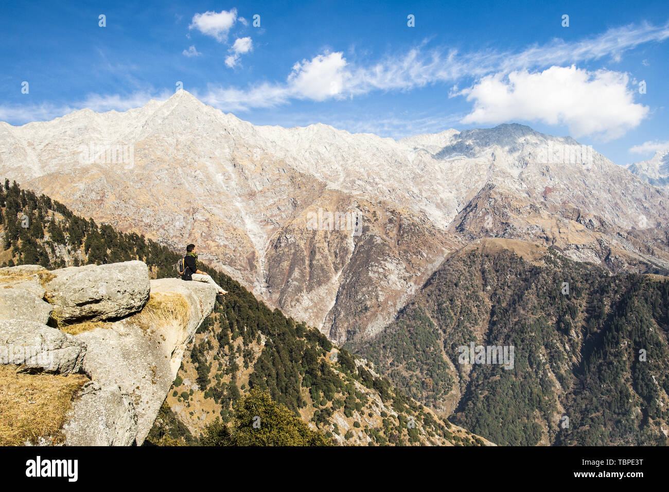 A tourist is sitting on a cliff enjoying the beautiful view of ...