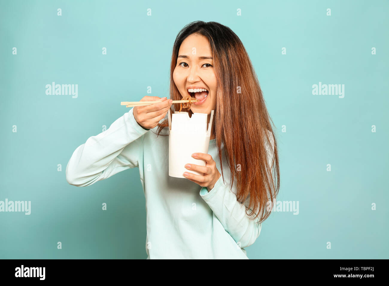 Asian woman eating delicious Chinese food on color background Stock ...
