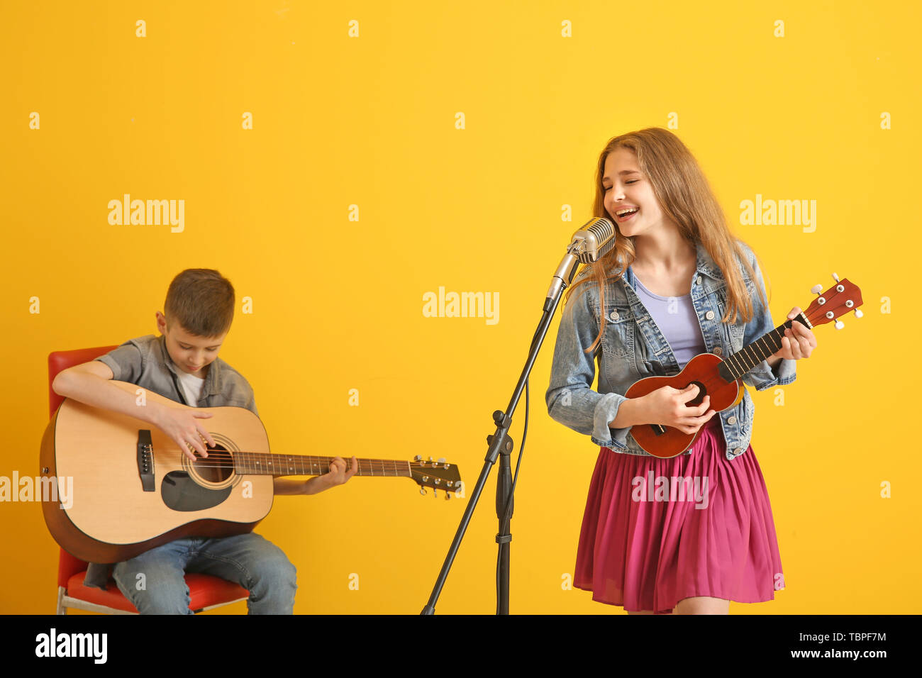 Teenage musicians playing against color background Stock Photo - Alamy