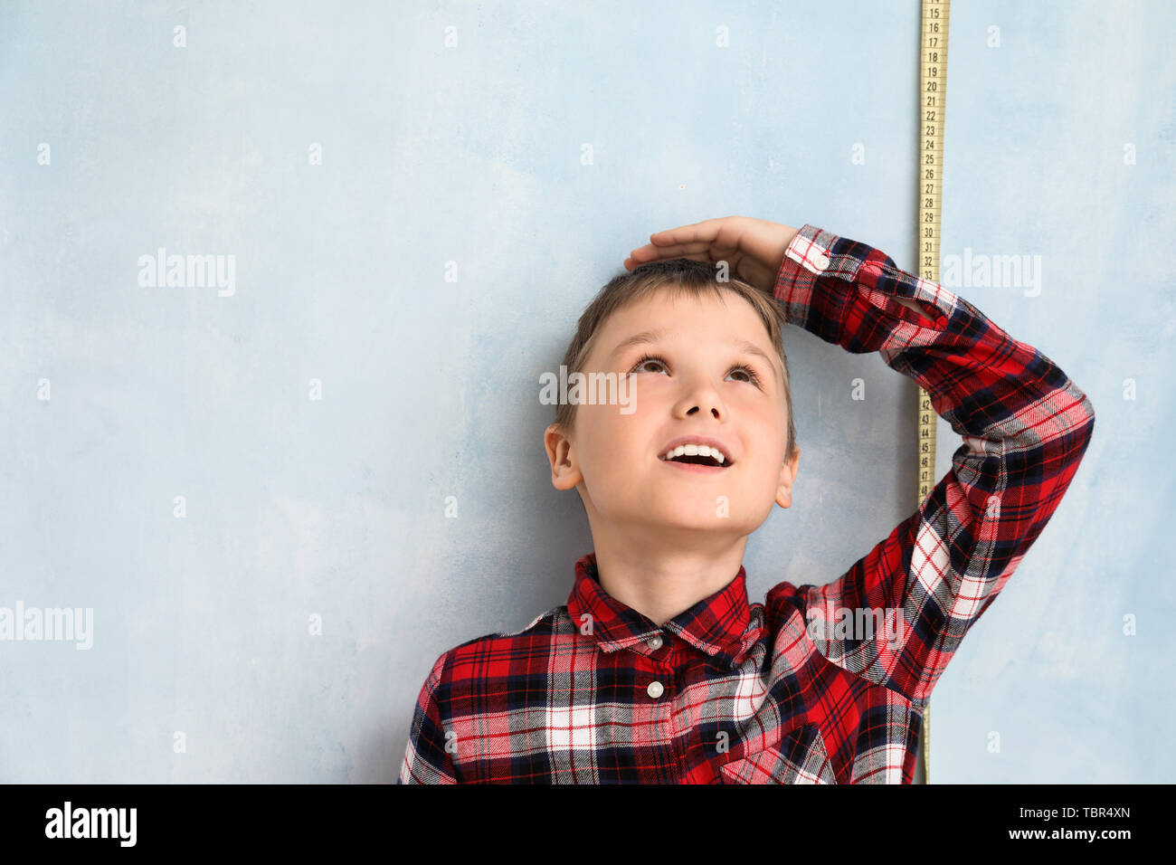 Cute little boy measuring height near color wall Stock Photo - Alamy