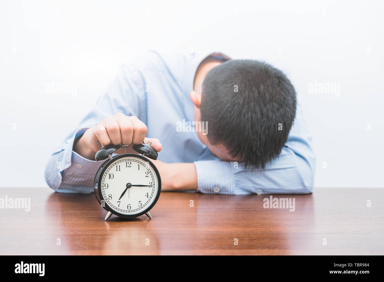 A tired young man holds the alarm clock Stock Photo - Alamy