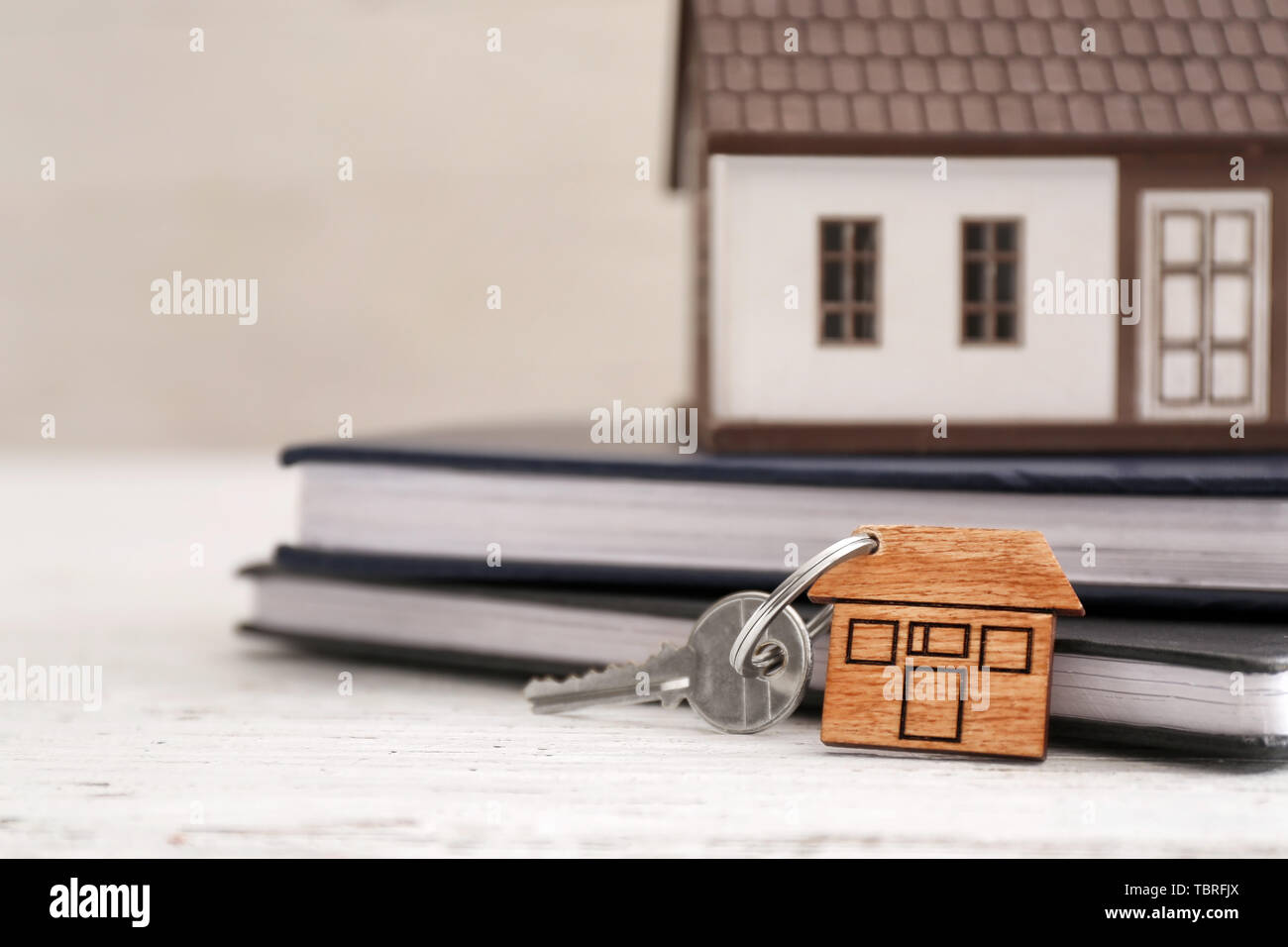 Model of house, books and key on table Stock Photo - Alamy