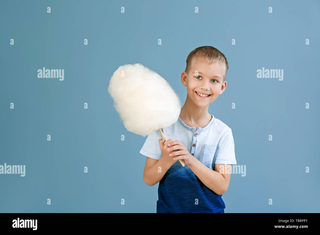 Cute little boy with cotton candy on color background Stock Photo - Alamy