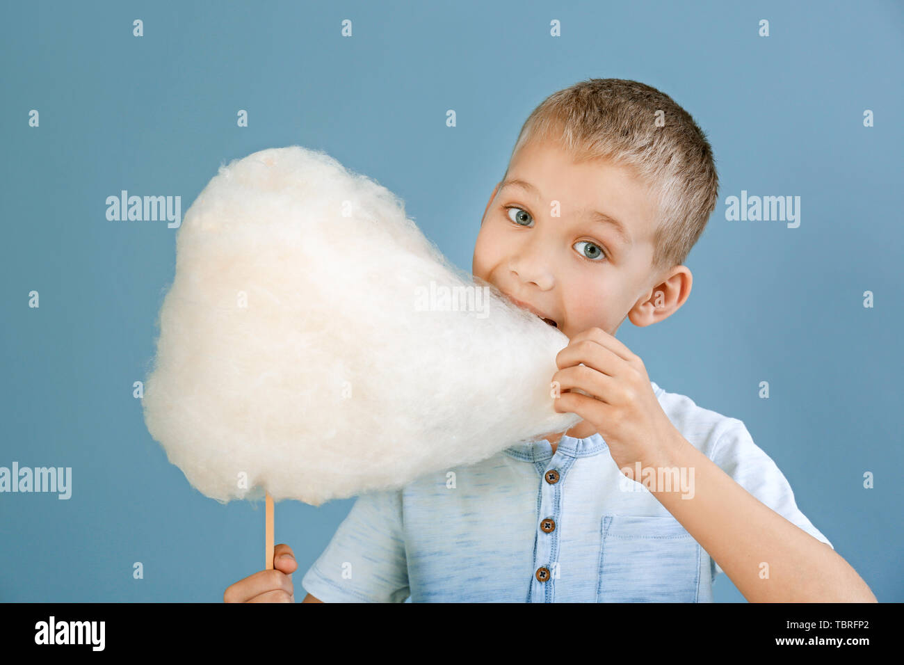 Cute little boy with cotton candy on color background Stock Photo - Alamy