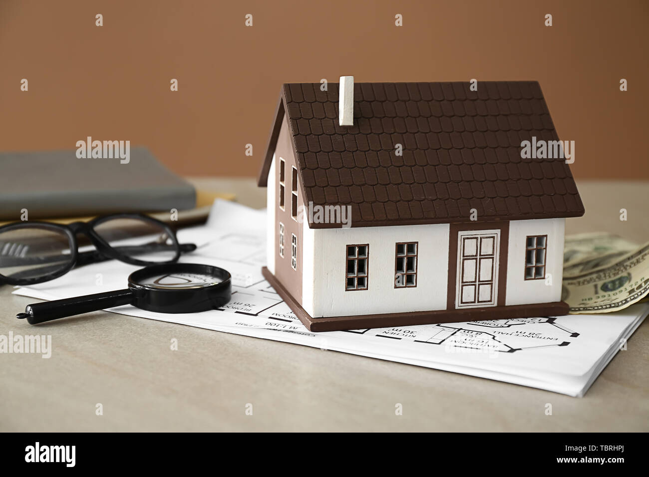 Figure of house, magnifier, money and drawing on table. Concept of ...