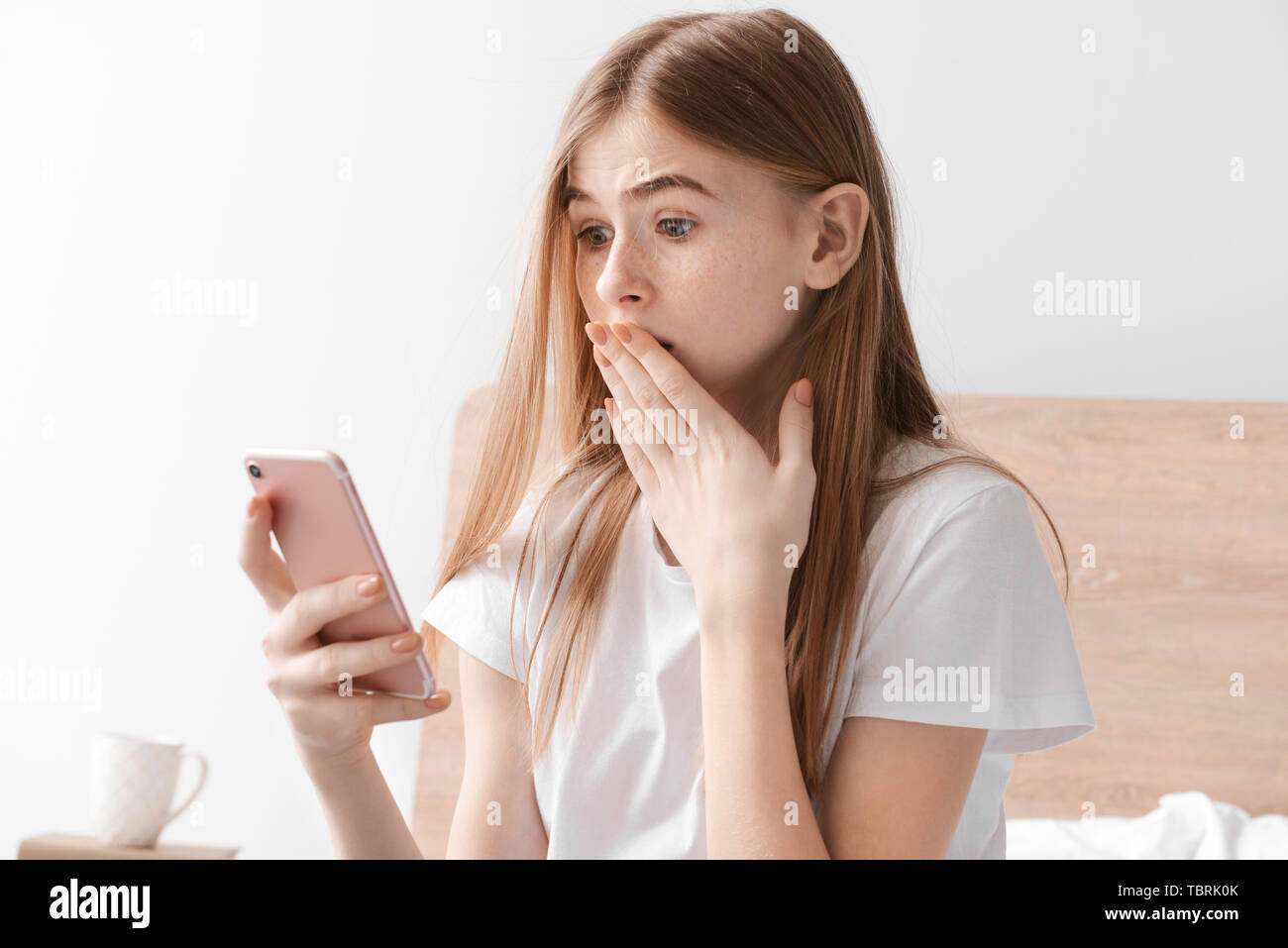 Afraid teenage girl with mobile phone in bedroom at home Stock Photo ...