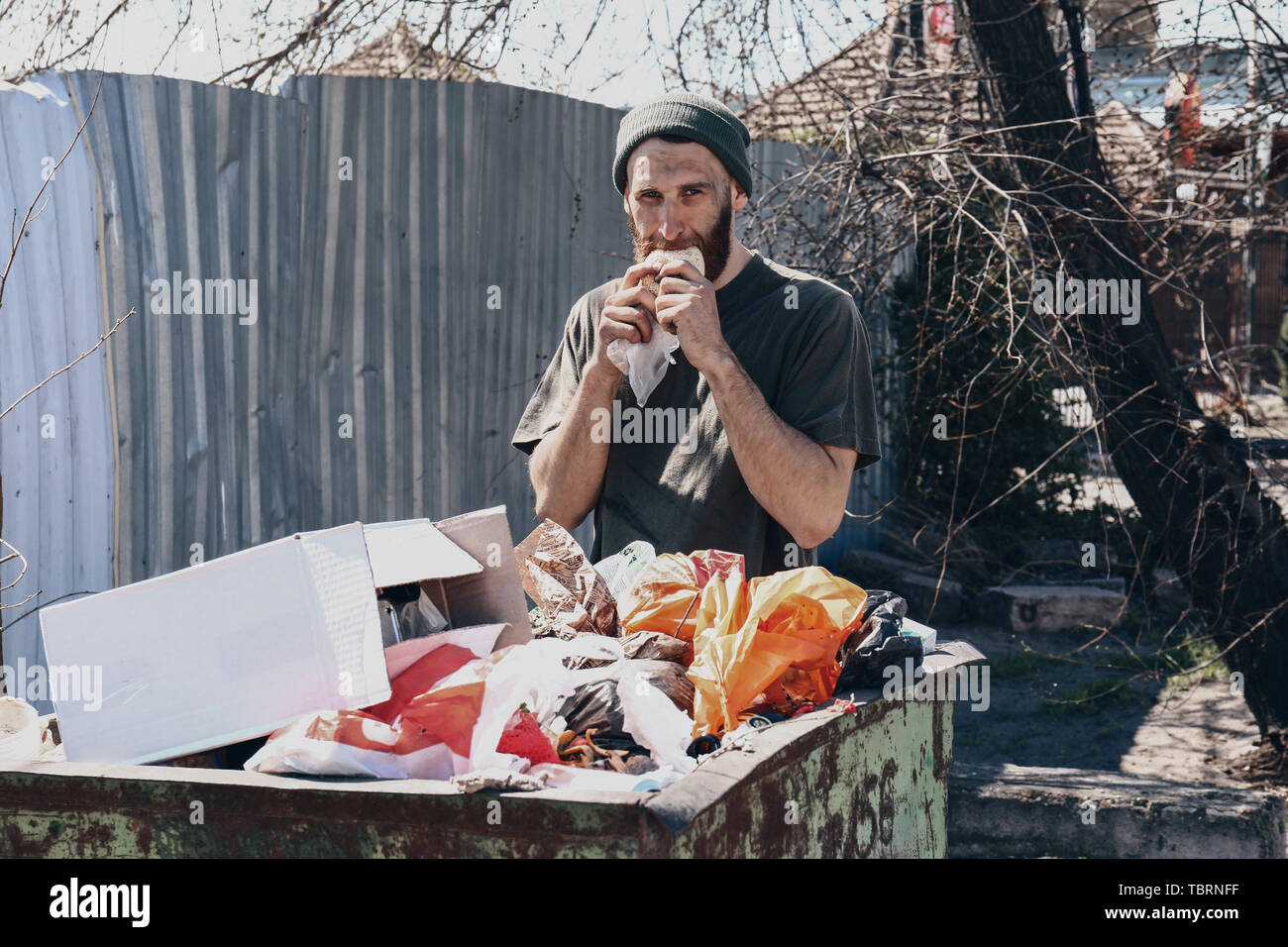Poor homeless man near trash bin outdoors Stock Photo - Alamy