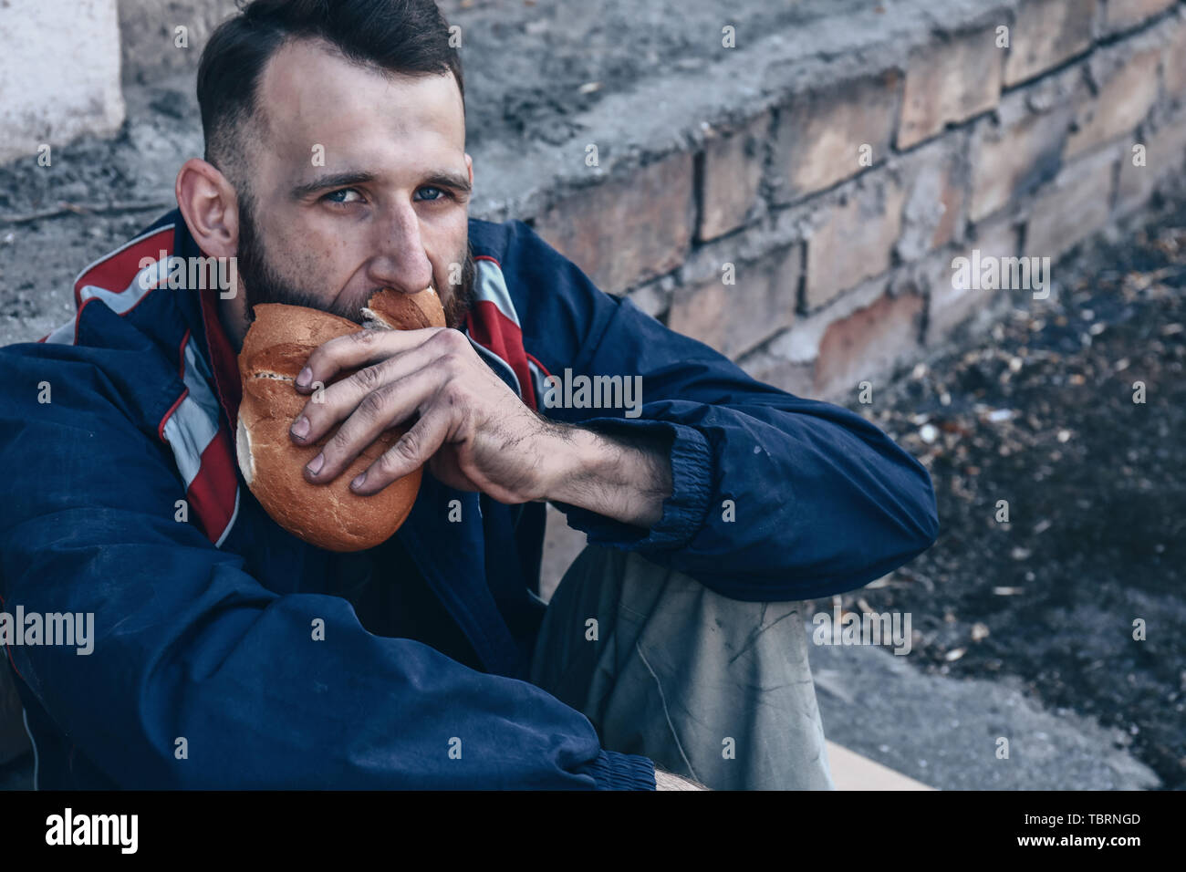 Poor homeless man eating bread outdoors Stock Photo - Alamy