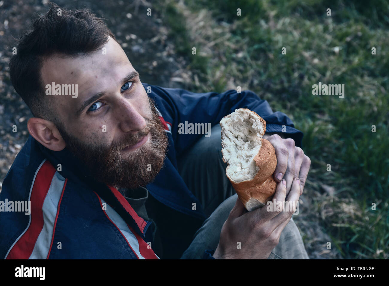 Poor homeless man eating bread outdoors Stock Photo - Alamy