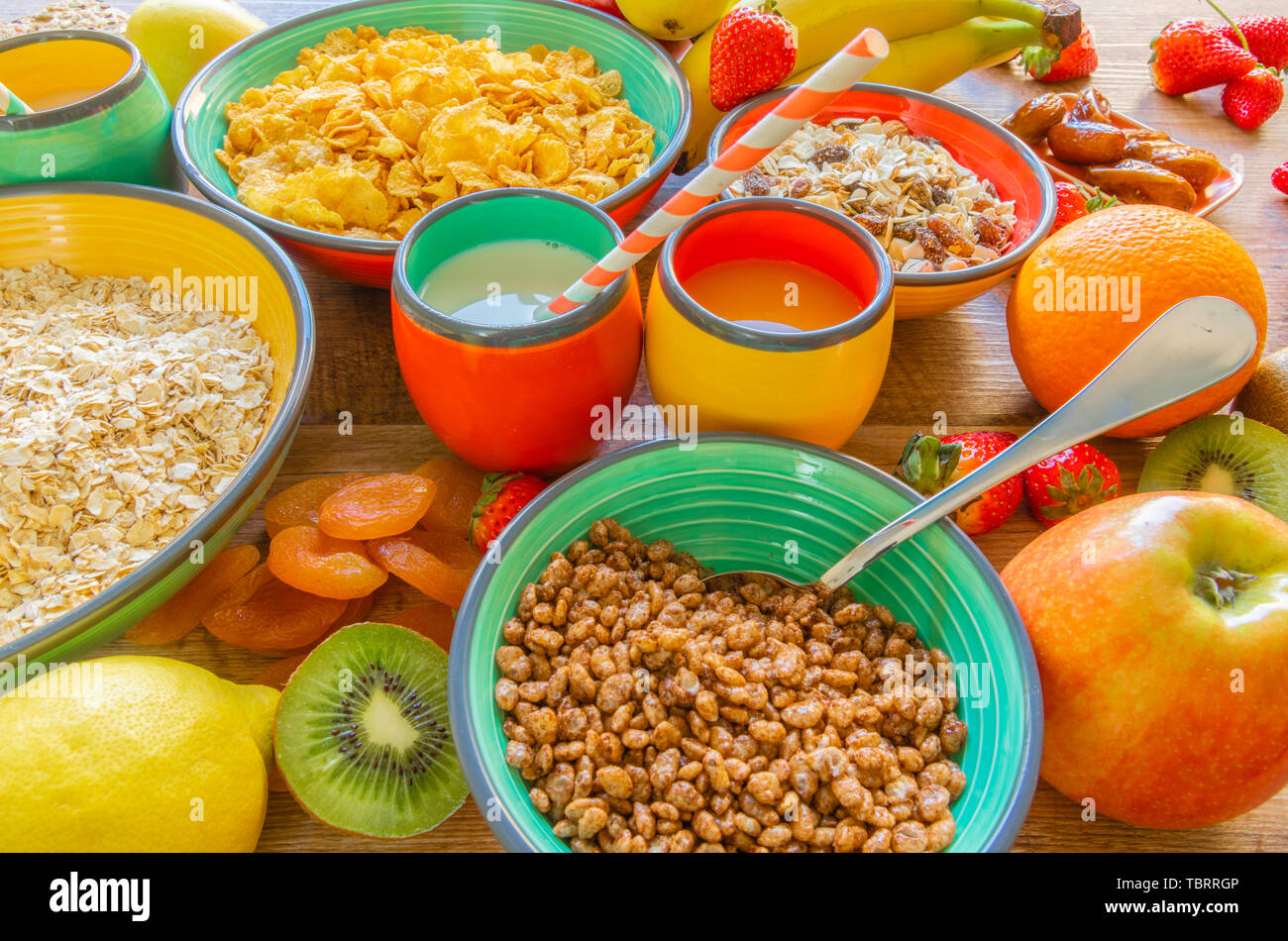 Assorted breakfast cereals, fruits and juices above a yellow table ...