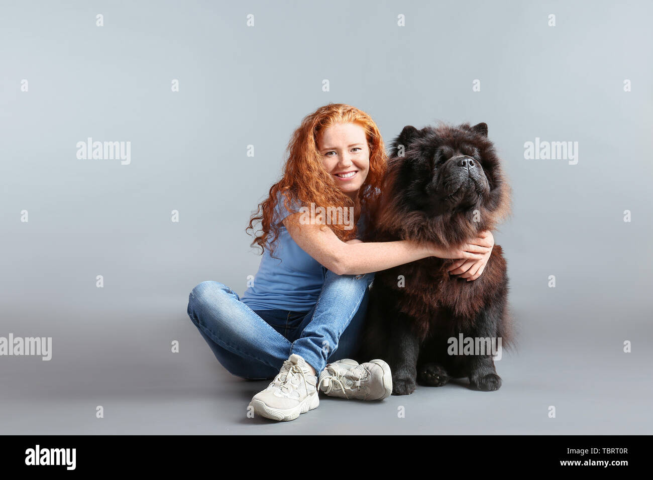 Young woman with cute Chow-Chow dog on grey background Stock Photo - Alamy