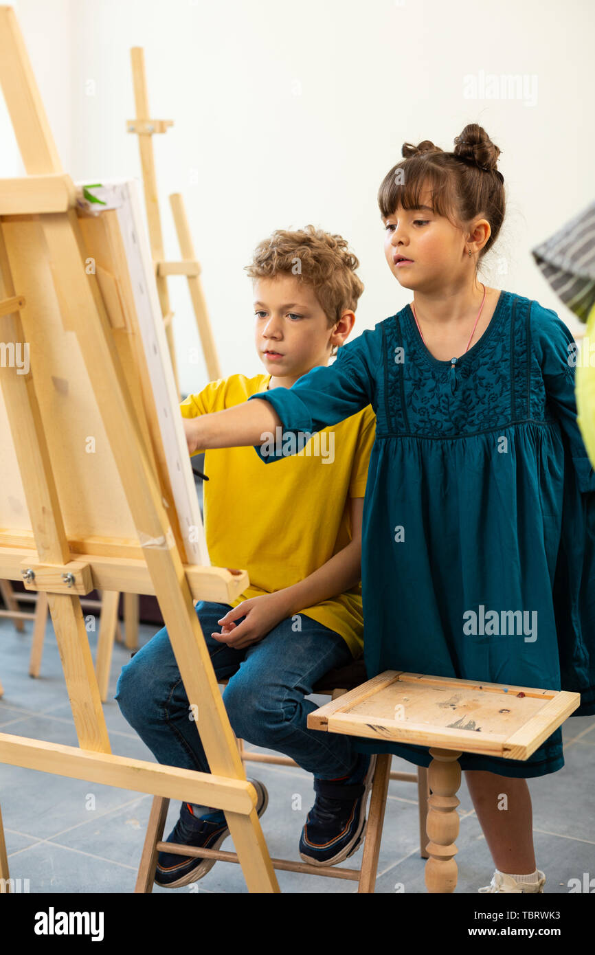 Cute girl helping. Cute dark-haired girl helping her blonde-haired ...