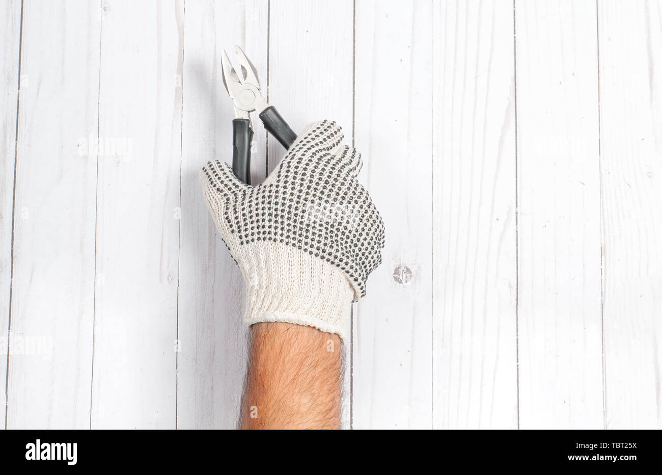 Tool. Hand in glove is holding pliers isolated on white wooden ...