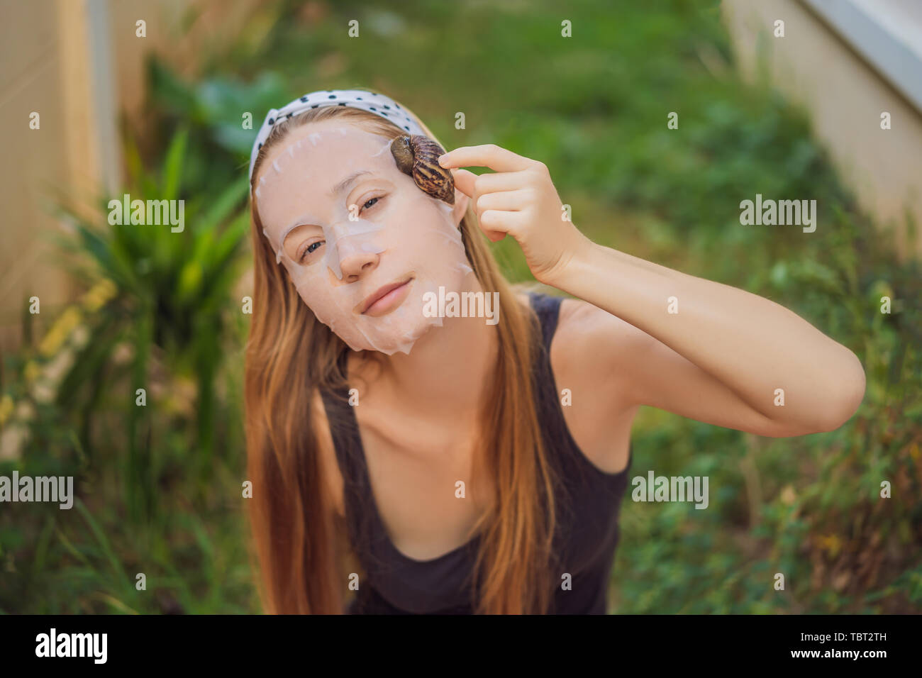 A young woman makes a face mask with snail mucus. Snail crawling on a ...