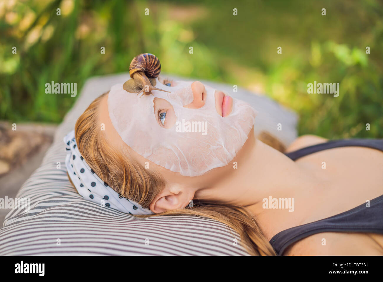 Young woman makes a face mask with snail mucus. Snail crawling on a ...