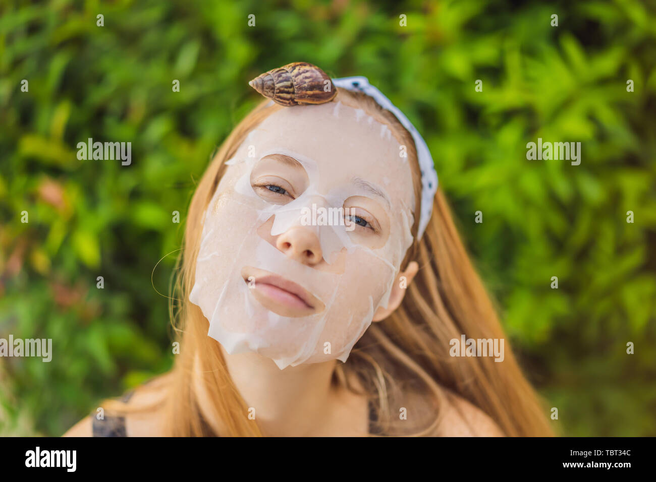 A young woman makes a face mask with snail mucus. Snail crawling on a ...