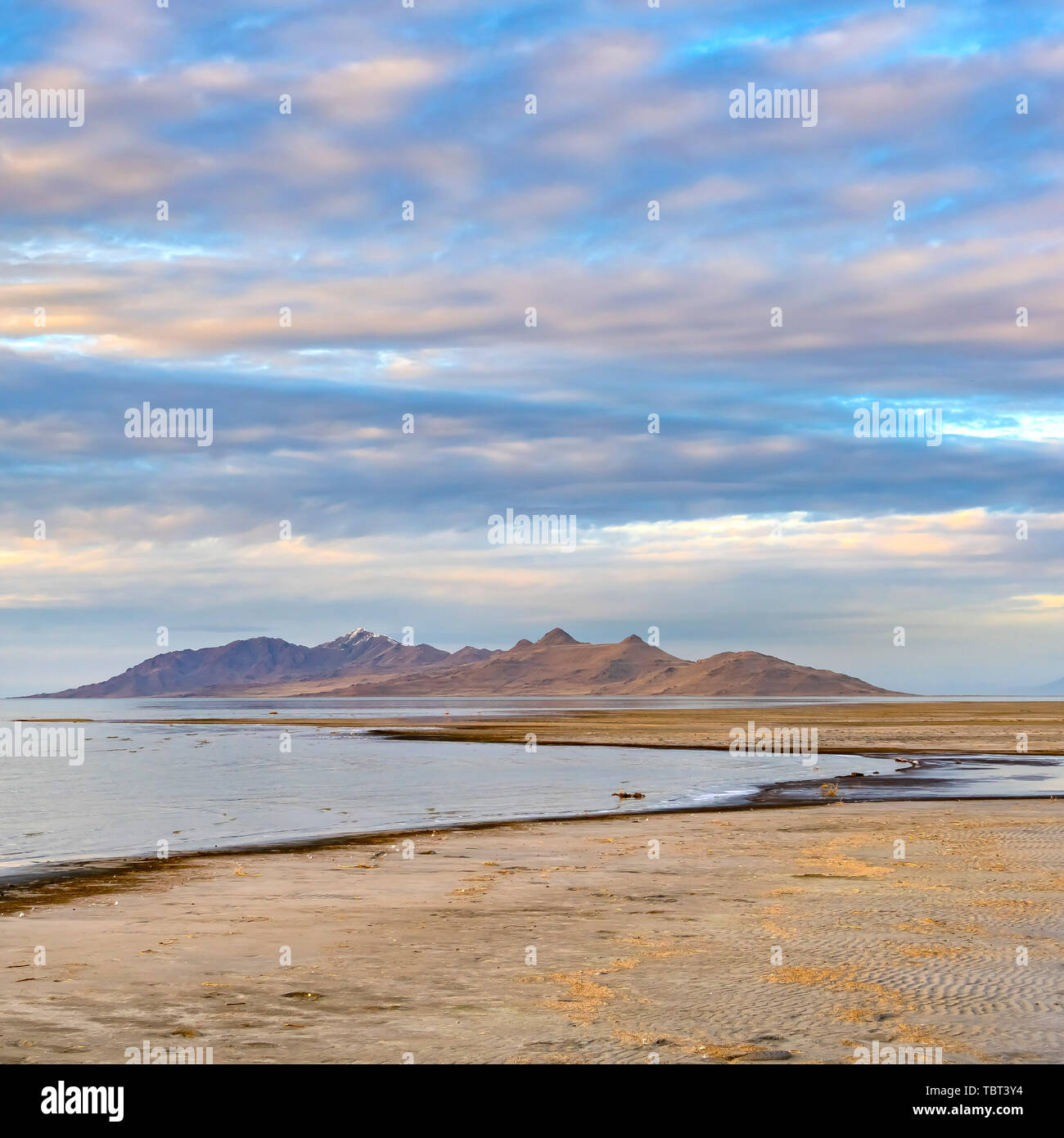 Square frame Gleaming lake with sandy shore and rugged mountain in the ...