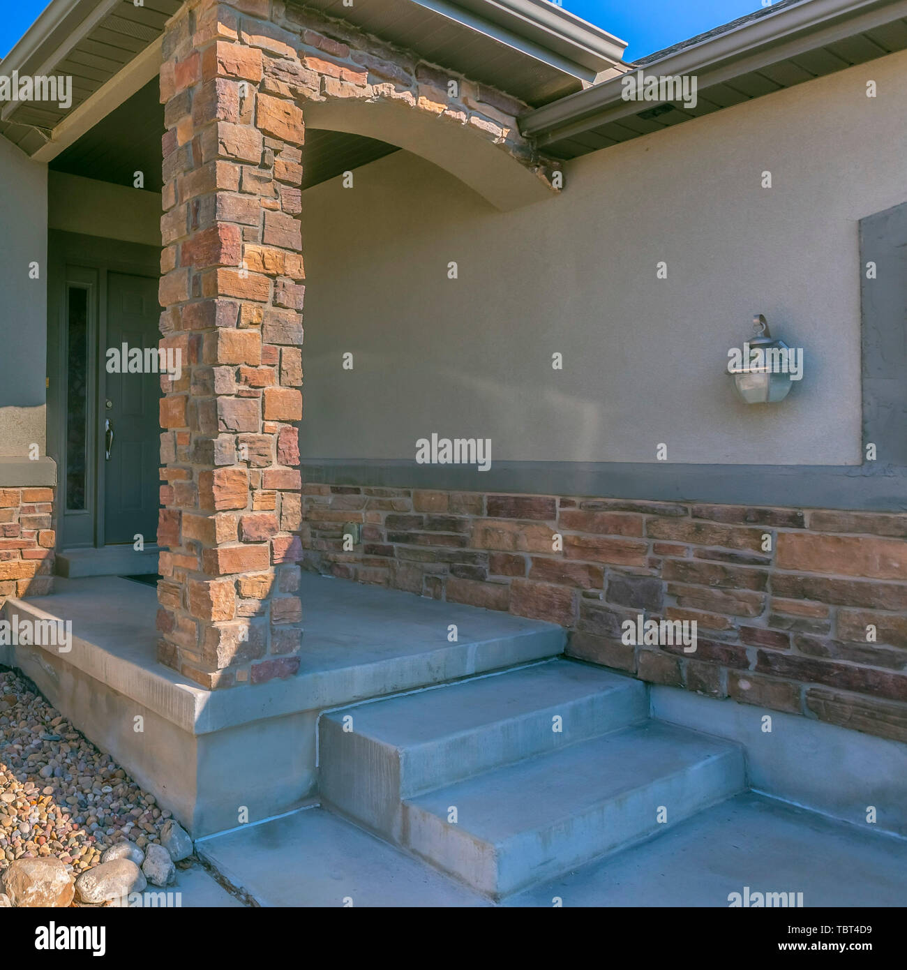 Square frame Facade of a home with a rocky yard and small front porch ...