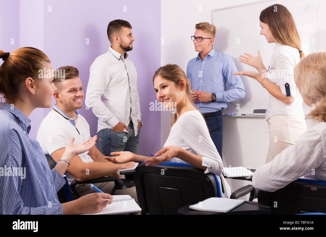 Happy young students talking with teacher and with each other on break ...