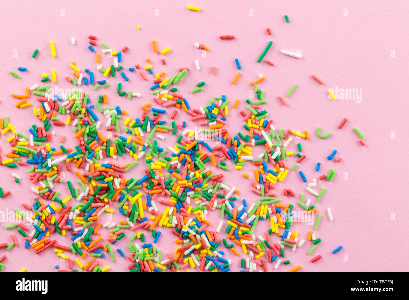Multi-colored sprinkles on pink background - cake topping sprinkles ...