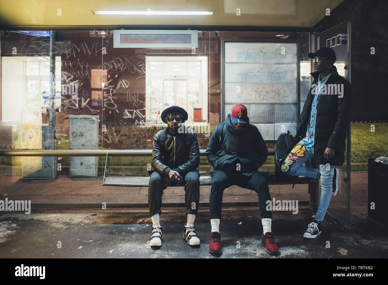 three young african men waiting on the bus stop - mobility, youth, new ...