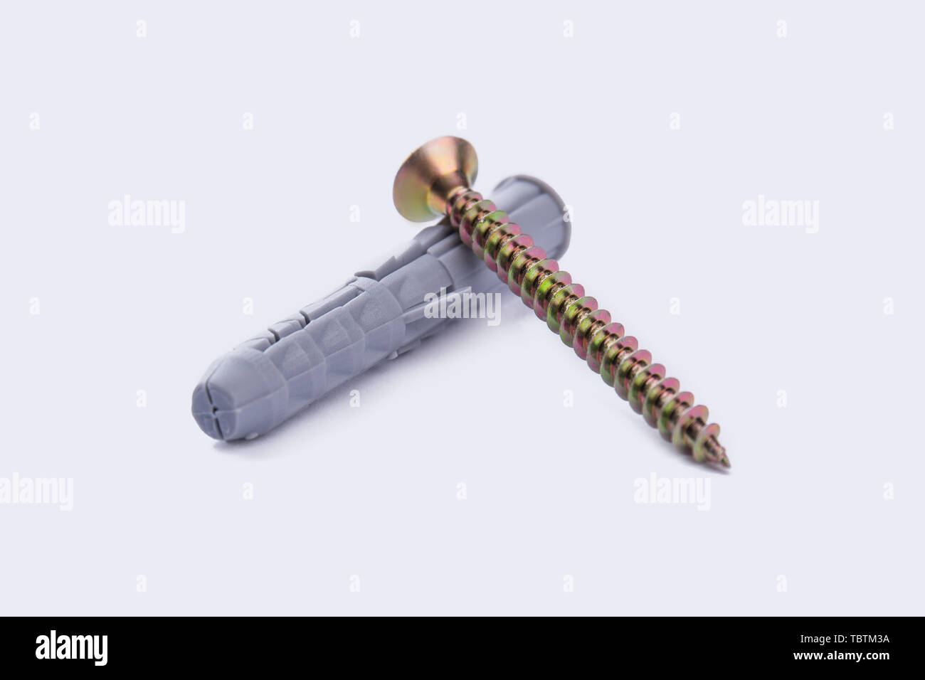 Screw and dowel. Gold screw and grey plastic dowel isolated on white ...