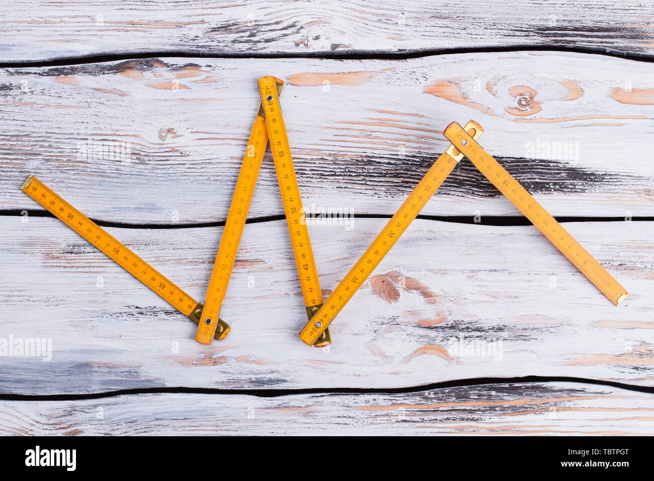 Yellow folding ruler on wooden background. Yellow meter on light wooden ...