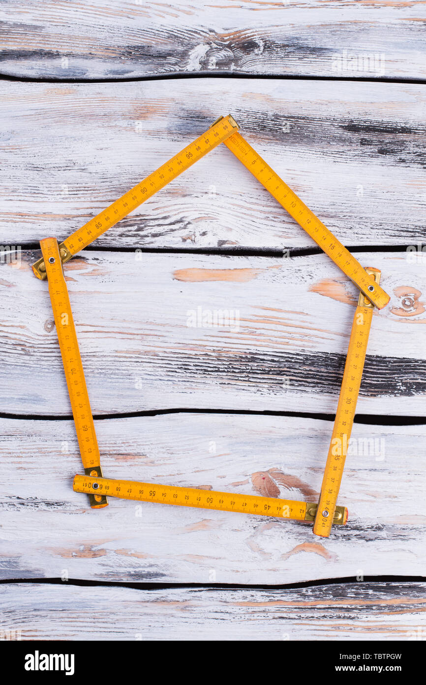 Yellow folding ruler forming shape of house. House-shaped yellow wooden ...